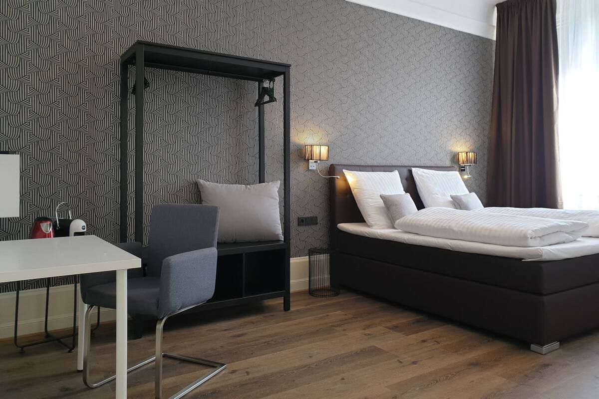 Quarto de hotel moderno com uma cama grande, uma mesa e uma cadeira.