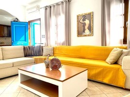 Uma sala de estar com um sofá amarelo, um sofá bege e uma mesa de centro de madeira.