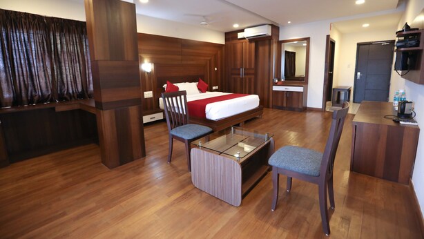 Quarto de hotel com cama, escrivaninha, cadeira, televisão e armário.