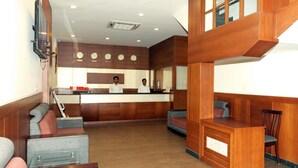 Um saguão de hotel com balcão de recepção, área de estar e escadaria.