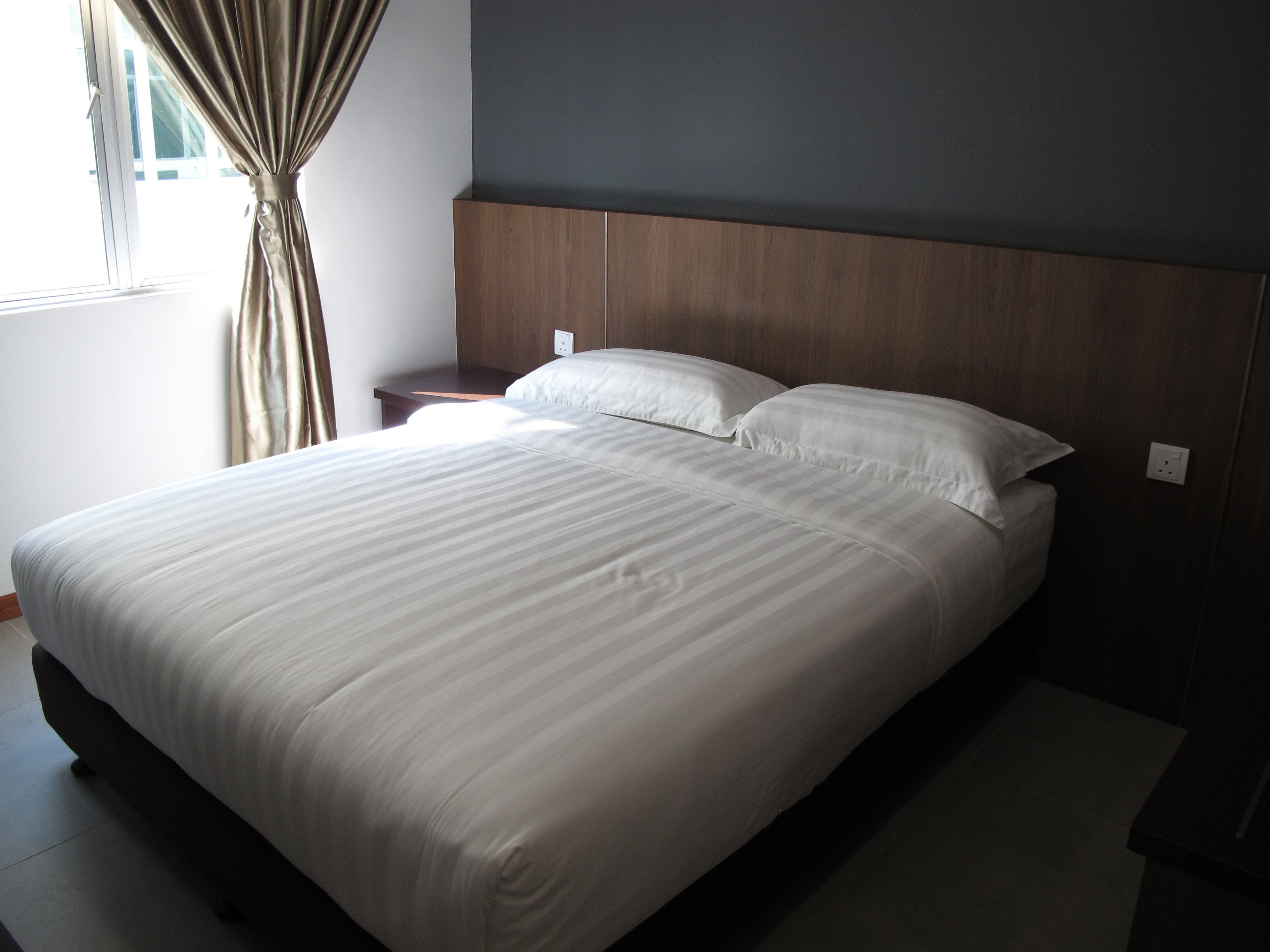 Cama bem arrumada com lençóis brancos em um quarto de hotel moderno.