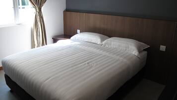 Cama bem arrumada com lençóis brancos em um quarto de hotel moderno.