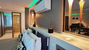 Quarto de hotel moderno com área de estar, um espelho grande e ar condicionado fixado na parede.