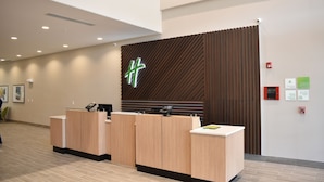 Balcão de recepção com design moderno, parede revestida de madeira com um logotipo e um alarme de incêndio na parede.
