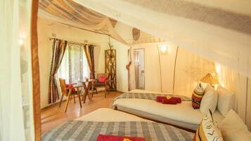 Quarto com duas camas, área de refeições e janela com cortinas.