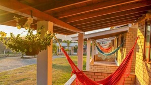 Uma área externa coberta com uma rede, uma planta pendente e uma parede de tijolos.
