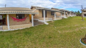 Uma fileira de edifícios térreos com estilo arquitetônico uniforme, com paredes de tijolo e telhados em cerâmica.