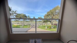 Uma varanda com vista para um parque, uma mesa pequena e duas cadeiras de vime.
