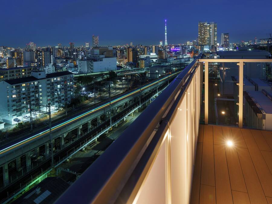 Um edifício alto com vista para um horizonte urbano, incluindo uma torre imponente e uma rodovia movimentada.