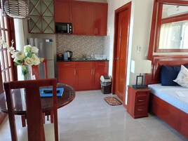 Quarto compacto com cama, pequena escrivaninha, mesa de refeições e cozinha compacta.