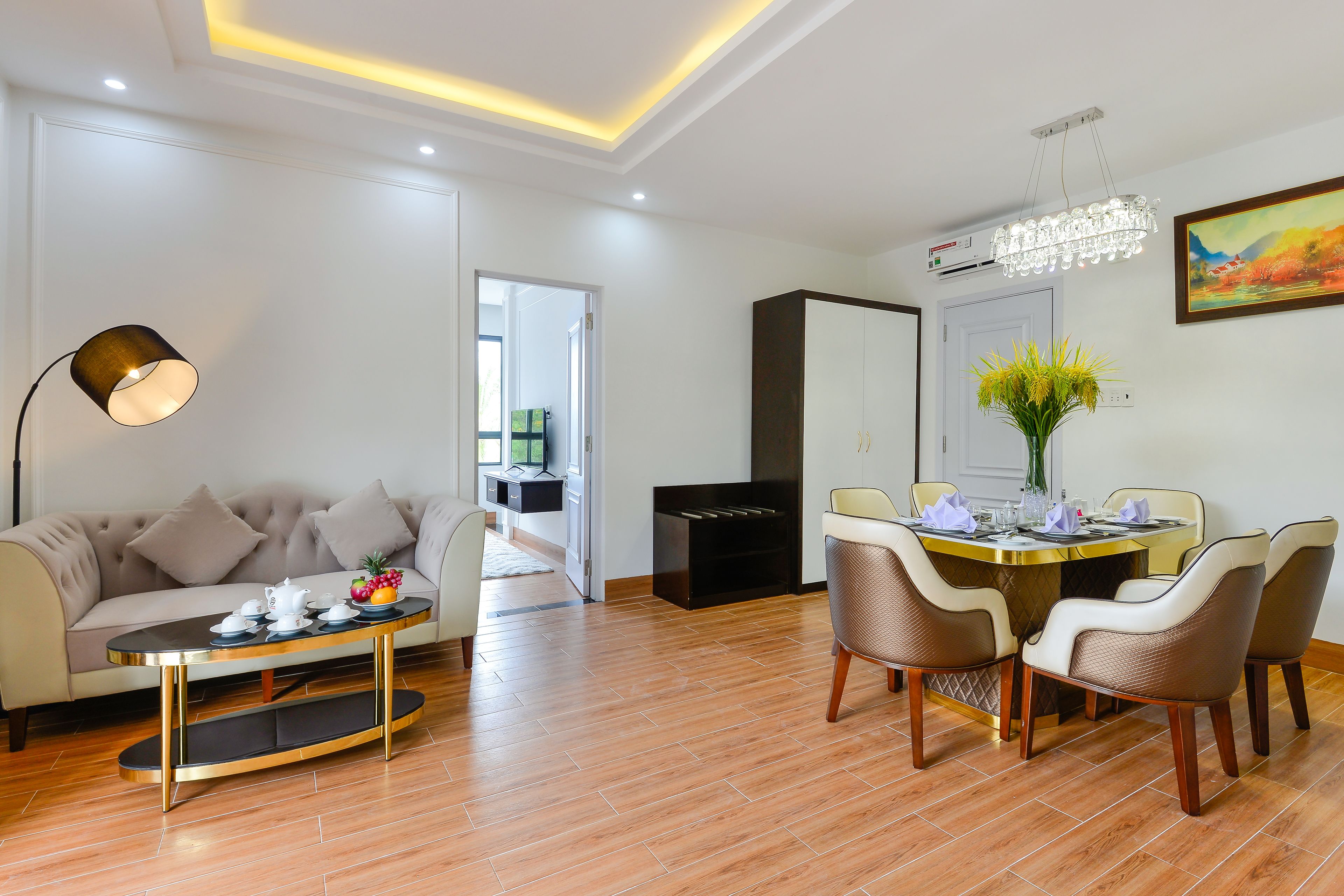 Uma sala de estar moderna com sofá, mesa de centro, mesa de jantar com cadeiras e um candelabro.