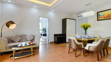Uma sala de estar moderna com sofá, mesa de centro, mesa de jantar com cadeiras e um candelabro.