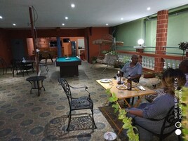 Uma mesa de bilhar, uma mesa de sinuca e um espaço de refeições com cadeiras e uma mesa posta para dois.