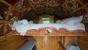 Quarto de sótão acolhedor com cama de madeira, um banco e vista para o exterior através de uma janela.