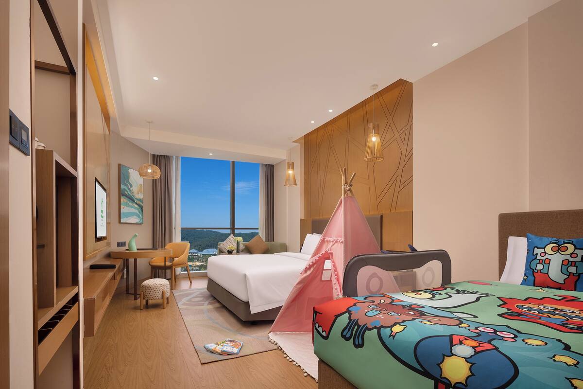 Quarto de hotel com cama, escrivaninha, cadeira, mesinha, janela com vista e uma estrutura parecida com uma tenda.
