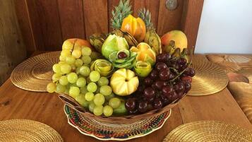 Uma cesta de frutas sobre uma mesa de madeira com jogos americanos trançados.