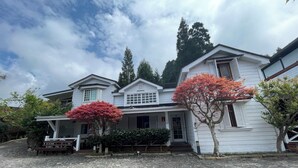 Uma casa de dois andares com um caminho de paralelepípedos e varanda.