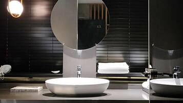 Casa de banho moderna com duas pias redondas, um espelho grande e um porta-toalhas.