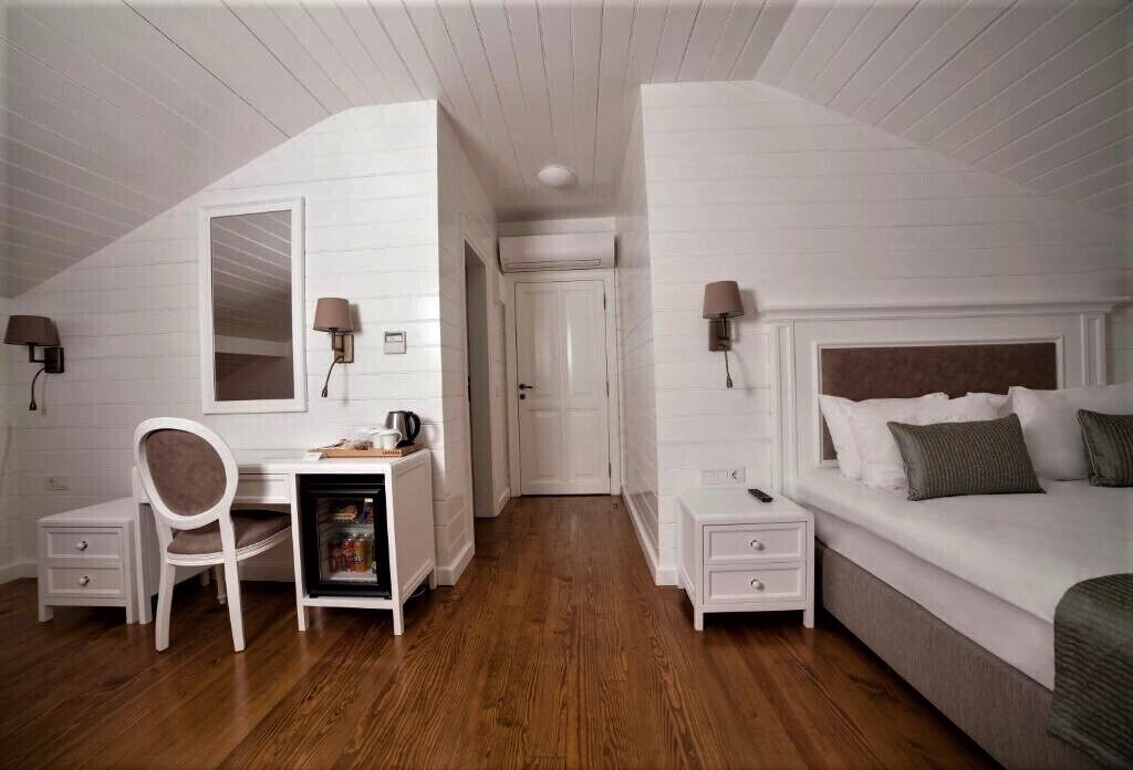 Quarto com cama, mesas de cabeceira, escrivaninha e uma cadeira.