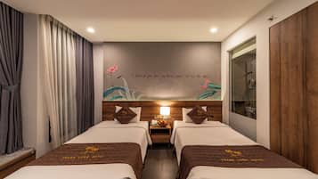 Quarto de hotel com duas camas, mesa de cabeceira com abajur, parede com mural floral e um espelho grande.