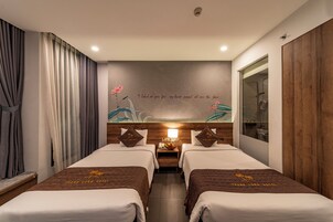 Quarto de hotel com duas camas, mesa de cabeceira com abajur, parede com mural floral e um espelho grande.