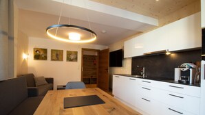 Cozinha moderna com armários brancos, mesa de jantar de madeira e luminária pendente.