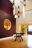 Um interior moderno com parede estampada, espelho redondo, mesa com design exclusivo e luminárias pendentes.