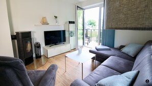 Uma sala de estar moderna com um sofá, uma televisão, uma mesinha e uma lareira.