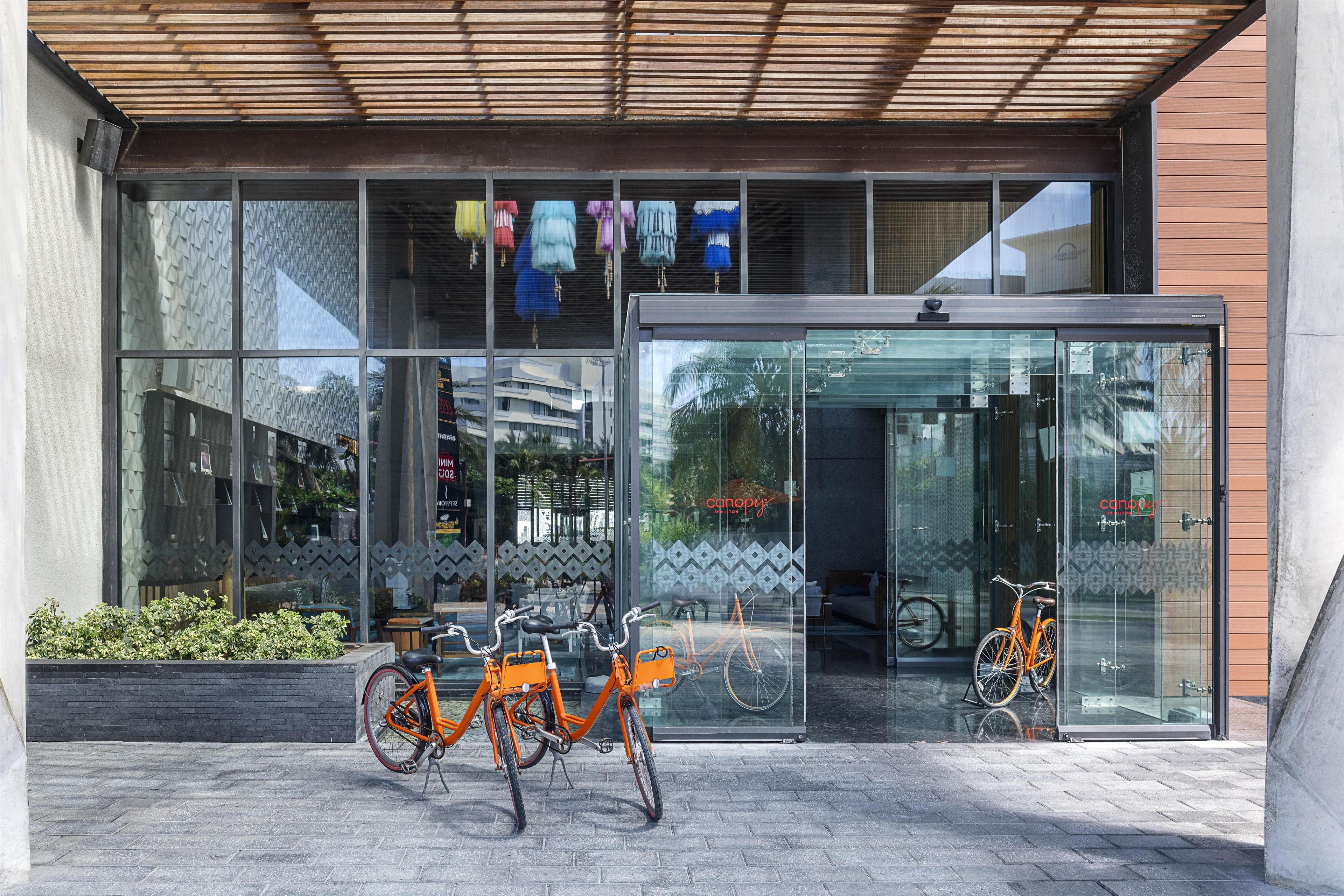 Um edifício moderno com grandes janelas, telhado de ripas de madeira e duas bicicletas estacionadas na frente.