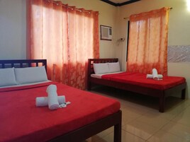 Duas camas de solteiro com roupa de cama vermelha, almofadas brancas e toalhas enroladas.