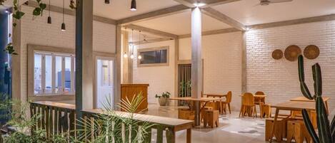 Um interior moderno com paredes de tijolo aparente, móveis de madeira e luminárias pendentes.