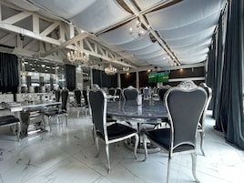 Uma sala de jantar com uma mesa de mármore, cadeiras estofadas pretas e lustres.