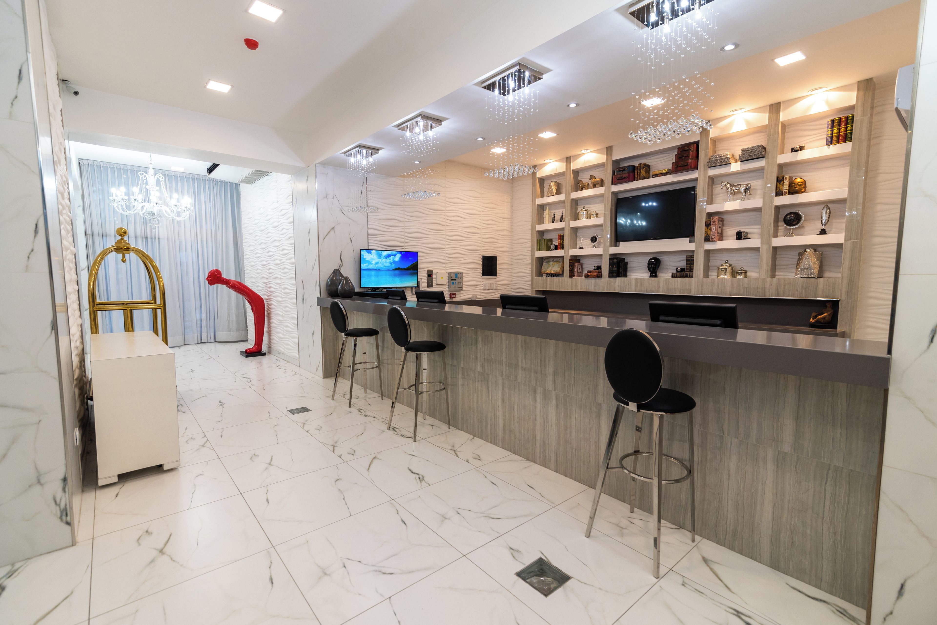 Uma área de bar moderna com piso de mármore, banquetas, uma televisão e prateleiras decorativas.
