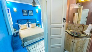 Quarto com cama, banheiro com pia e espelho, e tapete estampado.
