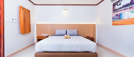 Quarto de hotel moderno com uma cama grande, mesa de cabeceira, ar condicionado fixado na parede e um cartaz.