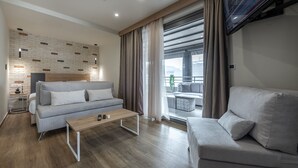 Uma sala de estar moderna com um sofá cinzento, uma mesa de centro de madeira e uma televisão fixada na parede.