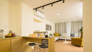 Um espaço compacto com cozinha compacta, área de refeições e sala de estar com sofá e poltronas.