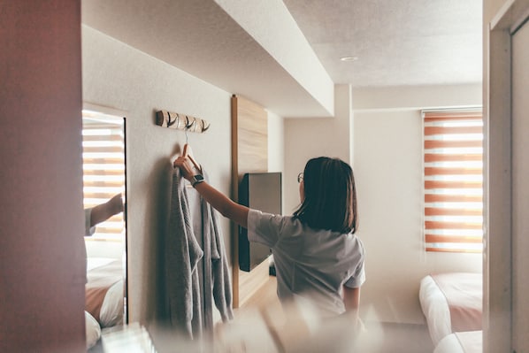 Um quarto com uma cama, um espelho e um cabideiro.