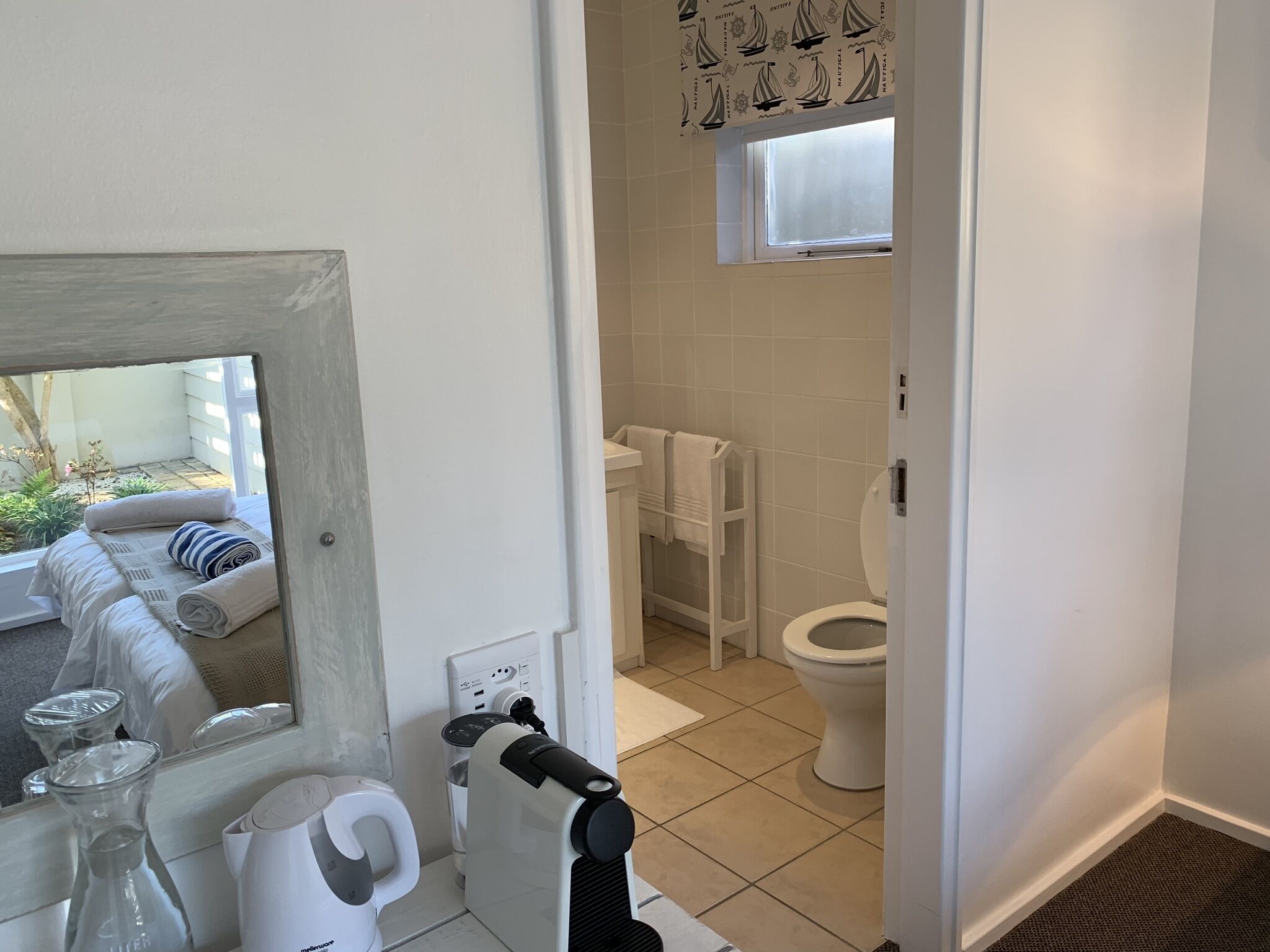 Casa de banho com sanita, uma pequena janela e um porta-toalhas.