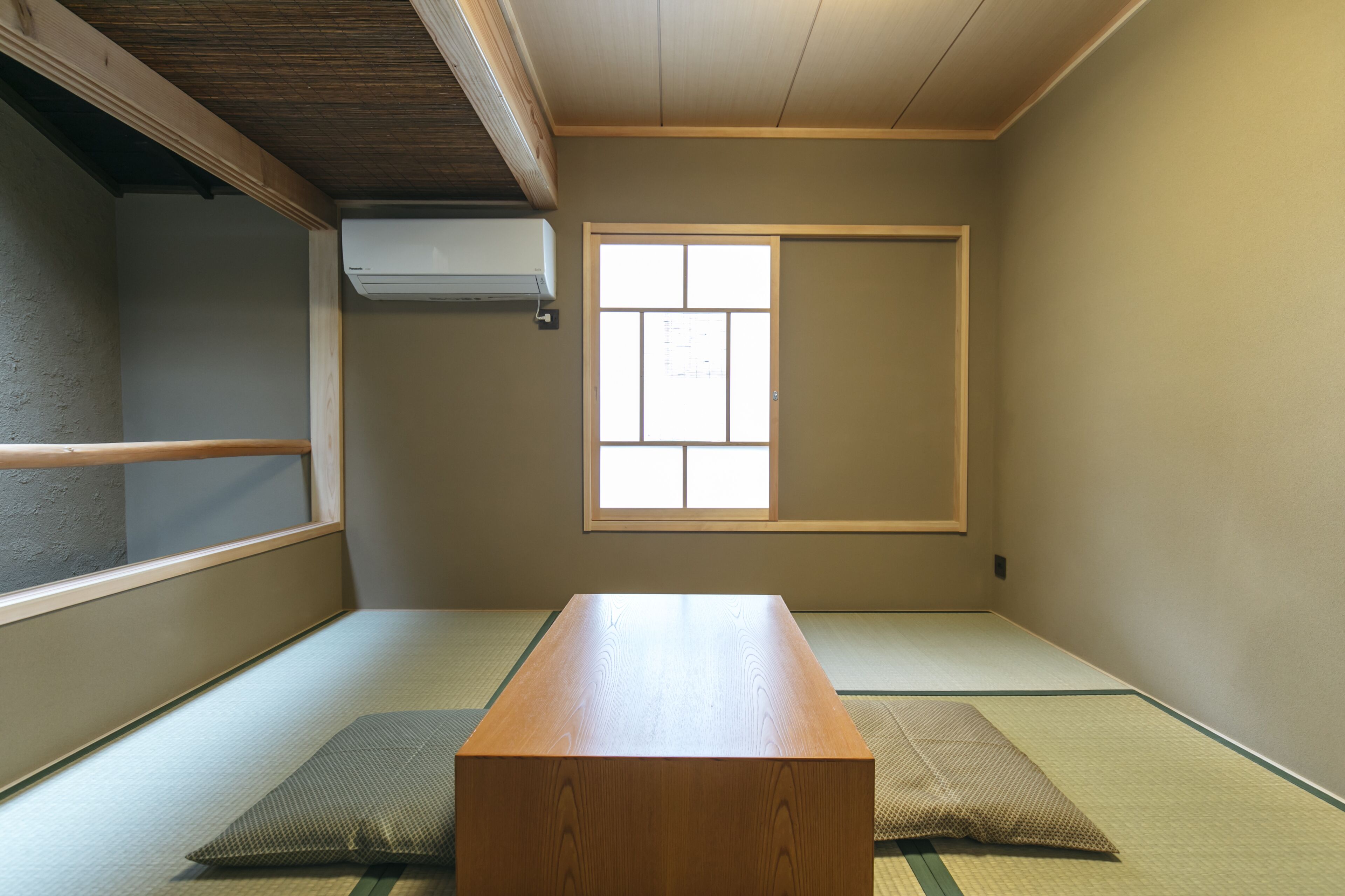 Um quarto japonês tradicional com tatames, uma mesa de madeira e um portas correderas.