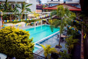 Uma área de piscina com vista clara, rodeada por vegetação exuberante e uma decoração de bandeira colorida.