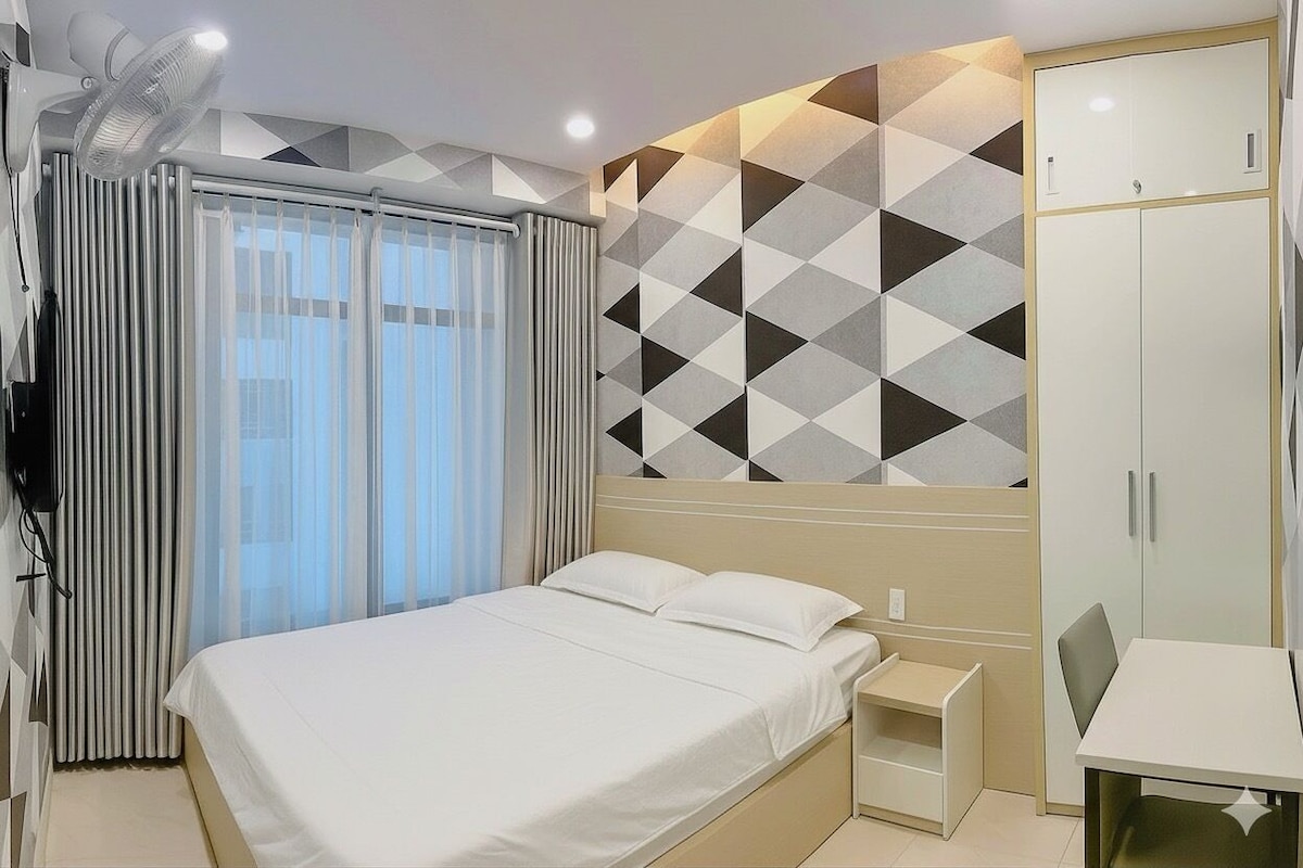Quarto de hotel moderno com cama, mesa de cabeceira e guarda-roupa.