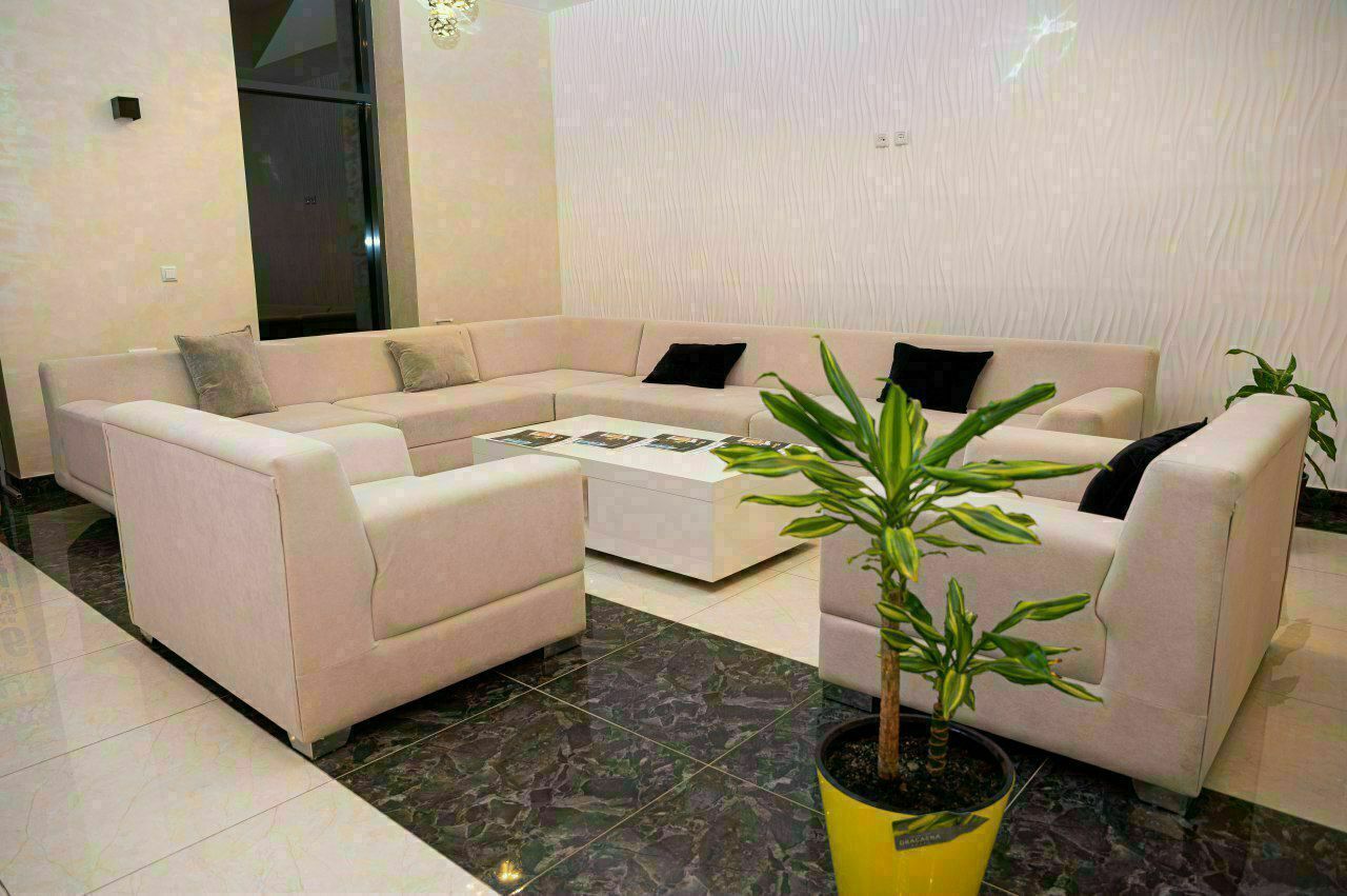 Uma sala de estar moderna com um sofá modular bege, uma mesa de centro e um vaso com planta.