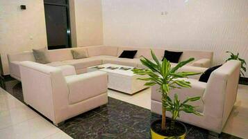 Uma sala de estar moderna com um sofá modular bege, uma mesa de centro e um vaso com planta.