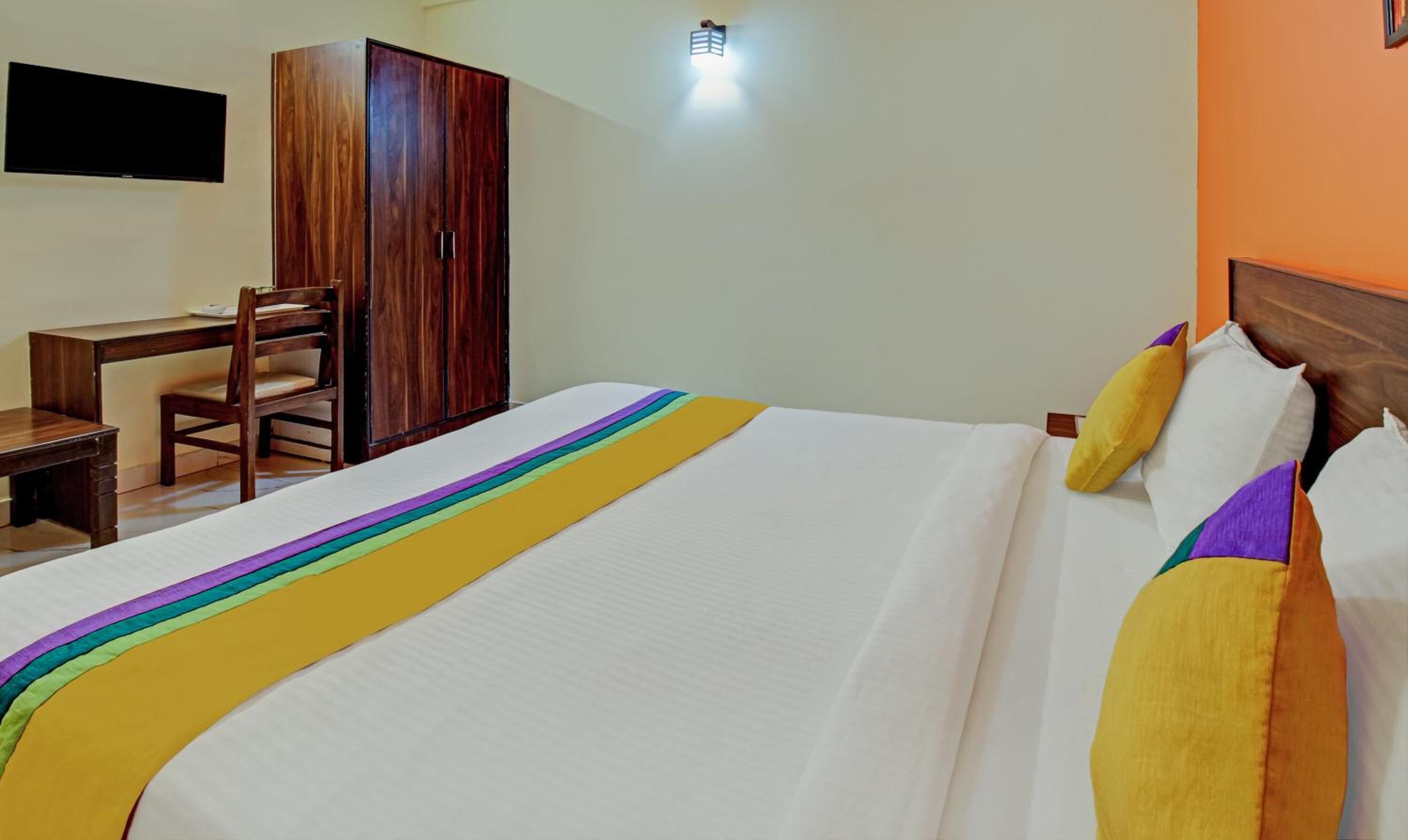 Quarto de hotel com uma cama, uma escrivaninha, uma cadeira e um guarda-roupa.