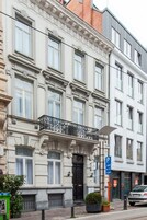 Um edifício de vários andares com estilo arquitetônico clássico, apresentando varandas ornamentadas e janelas amplas.