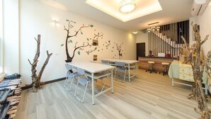 Quarto moderno e bem iluminado, com piso de madeira, uma mesa de jantar com cadeiras, uma escada e arte de parede com tema de árvores.