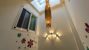 Quarto com claraboia, luminária decorativa alta e luminárias fixadas na parede.