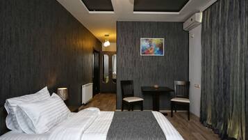 Quarto de hotel moderno com uma cama grande, uma escrivaninha, duas cadeiras e um quadro na parede.