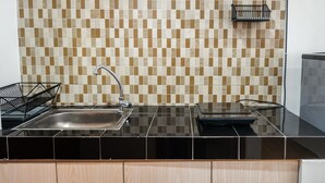 Uma cozinha com painel de azulejos, pia de aço inoxidável e bancada preta.